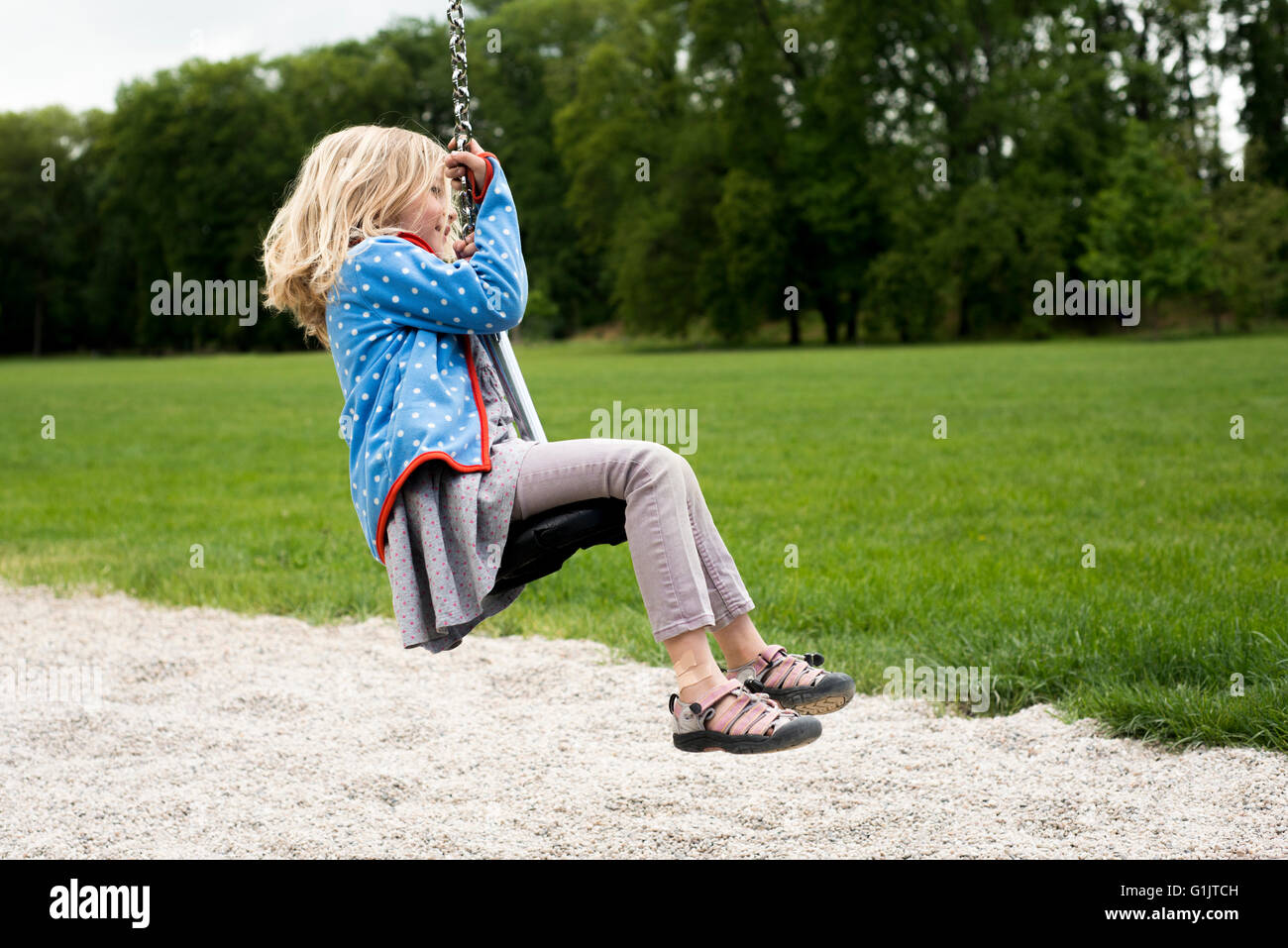Happy Child blond girl (age 5) rids on Flying Fox play equipment in a ...