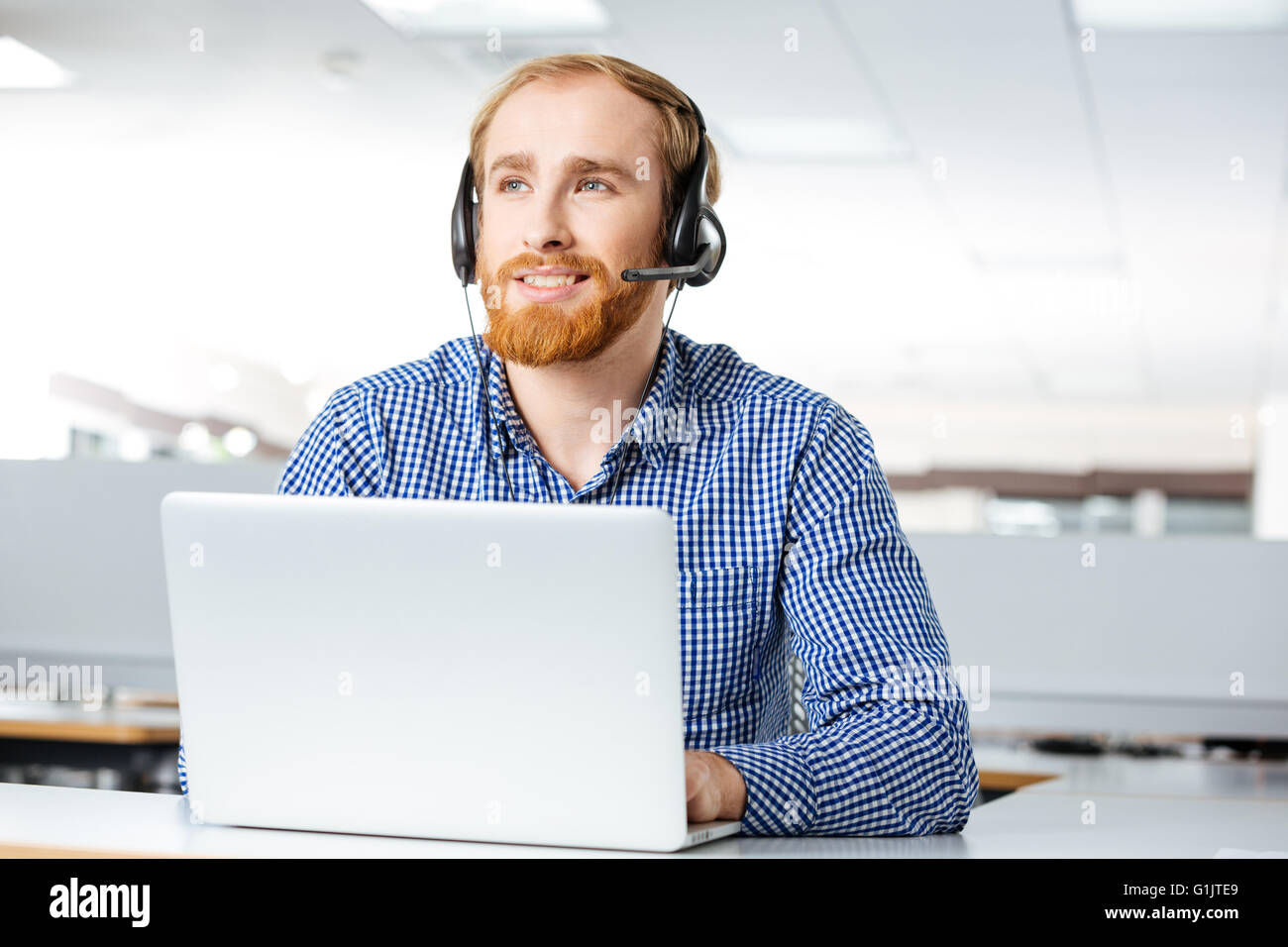 Happy handsome young man using headset and laptop in office Stock Photo ...