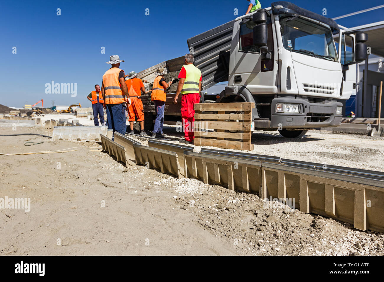 Workers are unloading material form truck for water during a heavy rain ...