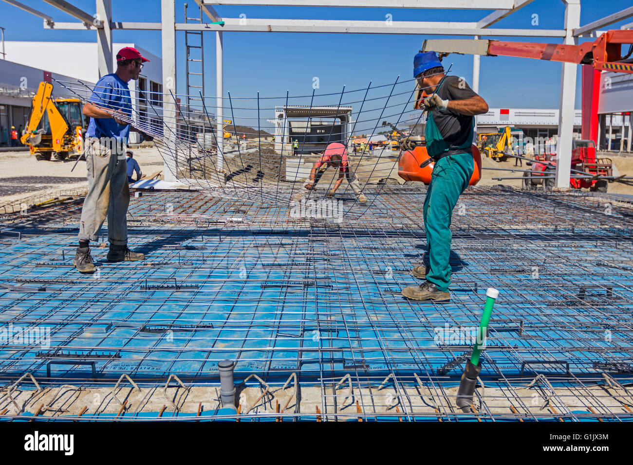 Construction workers installing reinforcement mesh at building site ...