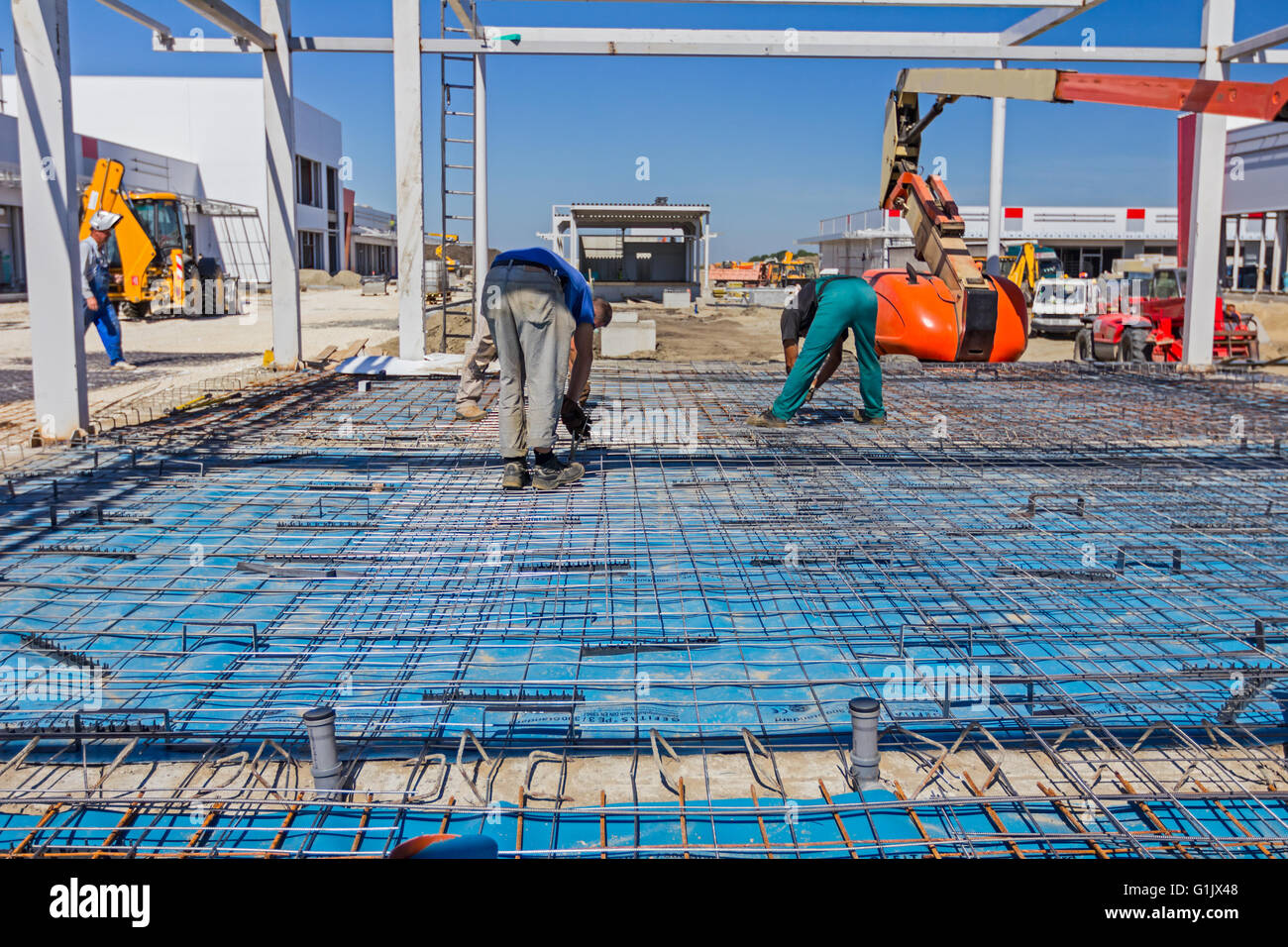 Construction workers installing reinforcement mesh at building site ...