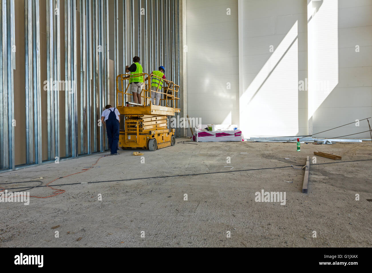 Workers are high up in cherry picker on building site Stock Photo - Alamy