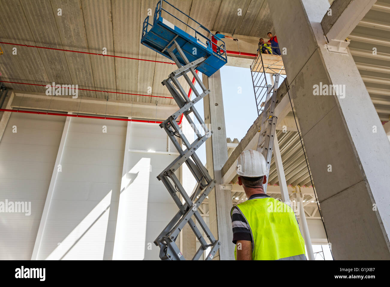 Tall scissor lift platform machine at construction site hi-res stock ...