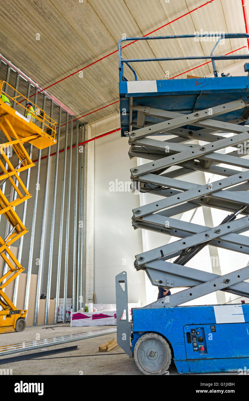 Workers are high up in cherry picker on building site Stock Photo - Alamy
