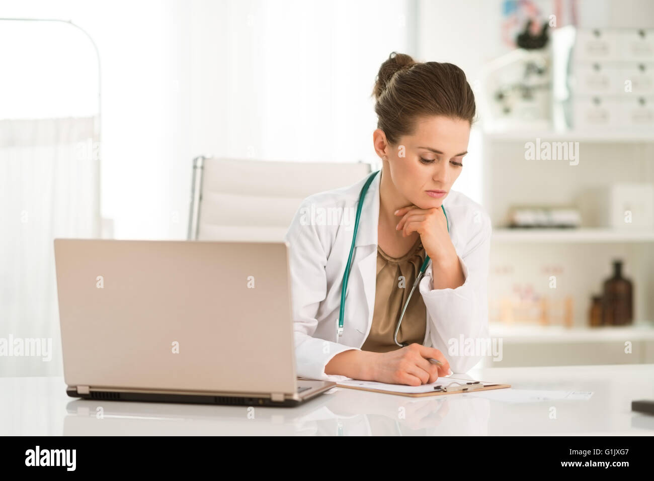 Modern health care. Thoughtful female doctor sitting at a desk in the ...