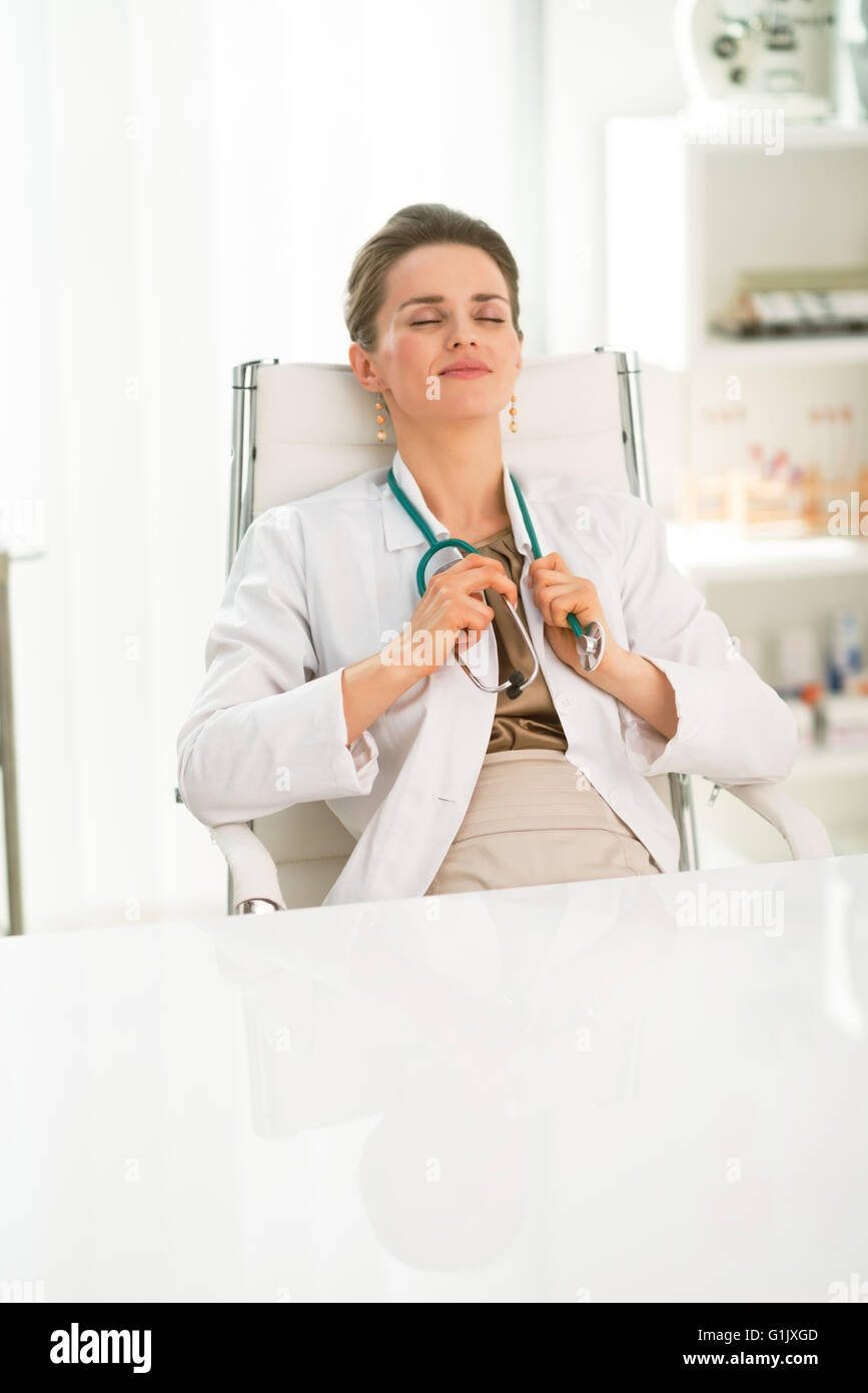 Modern health care. Relaxed female doctor sitting at a desk in the ...