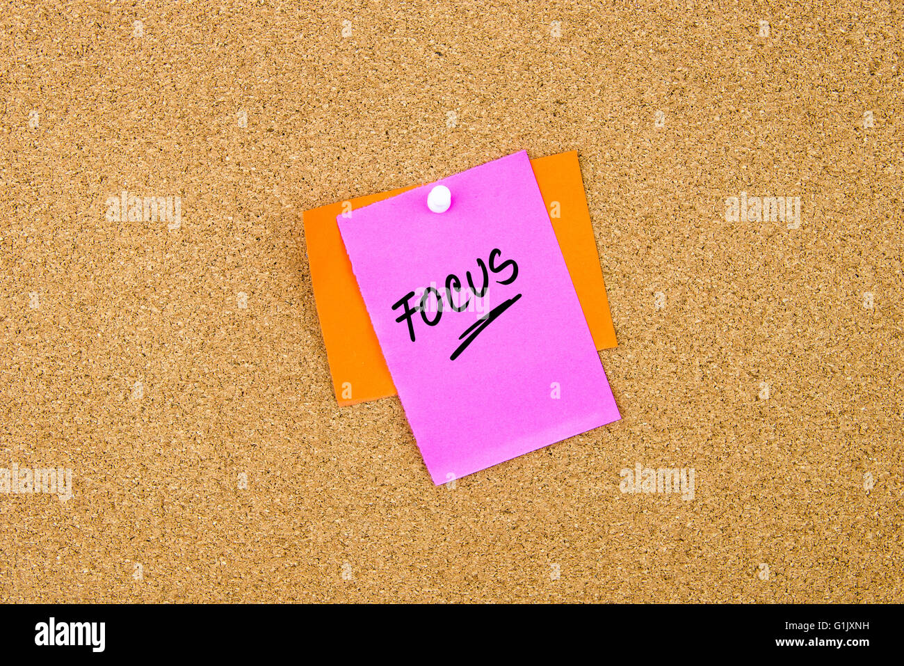 Focus written on paper note pinned on cork board with white thumbtack ...
