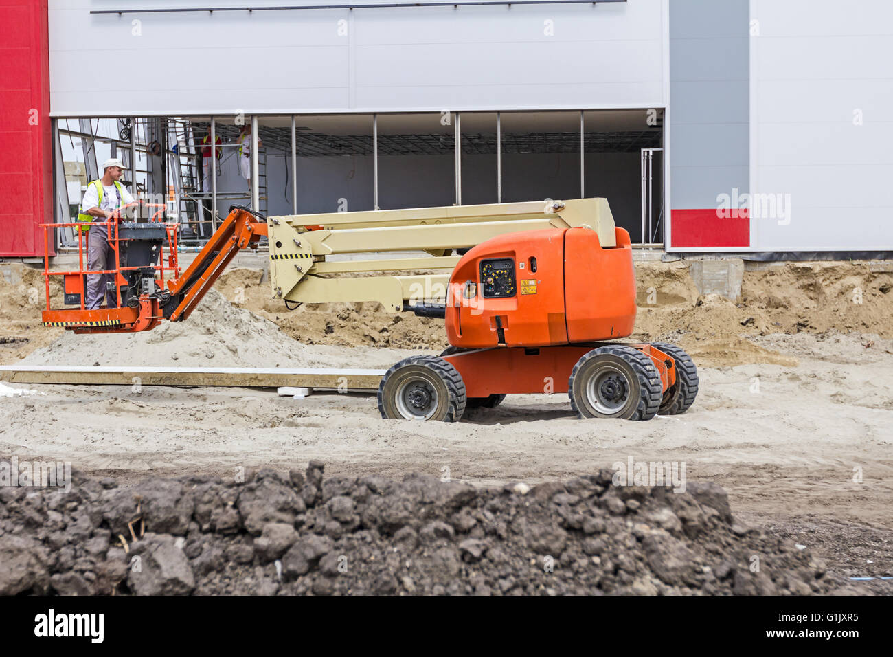 Worker is driving the cherry picker across building site Stock Photo ...