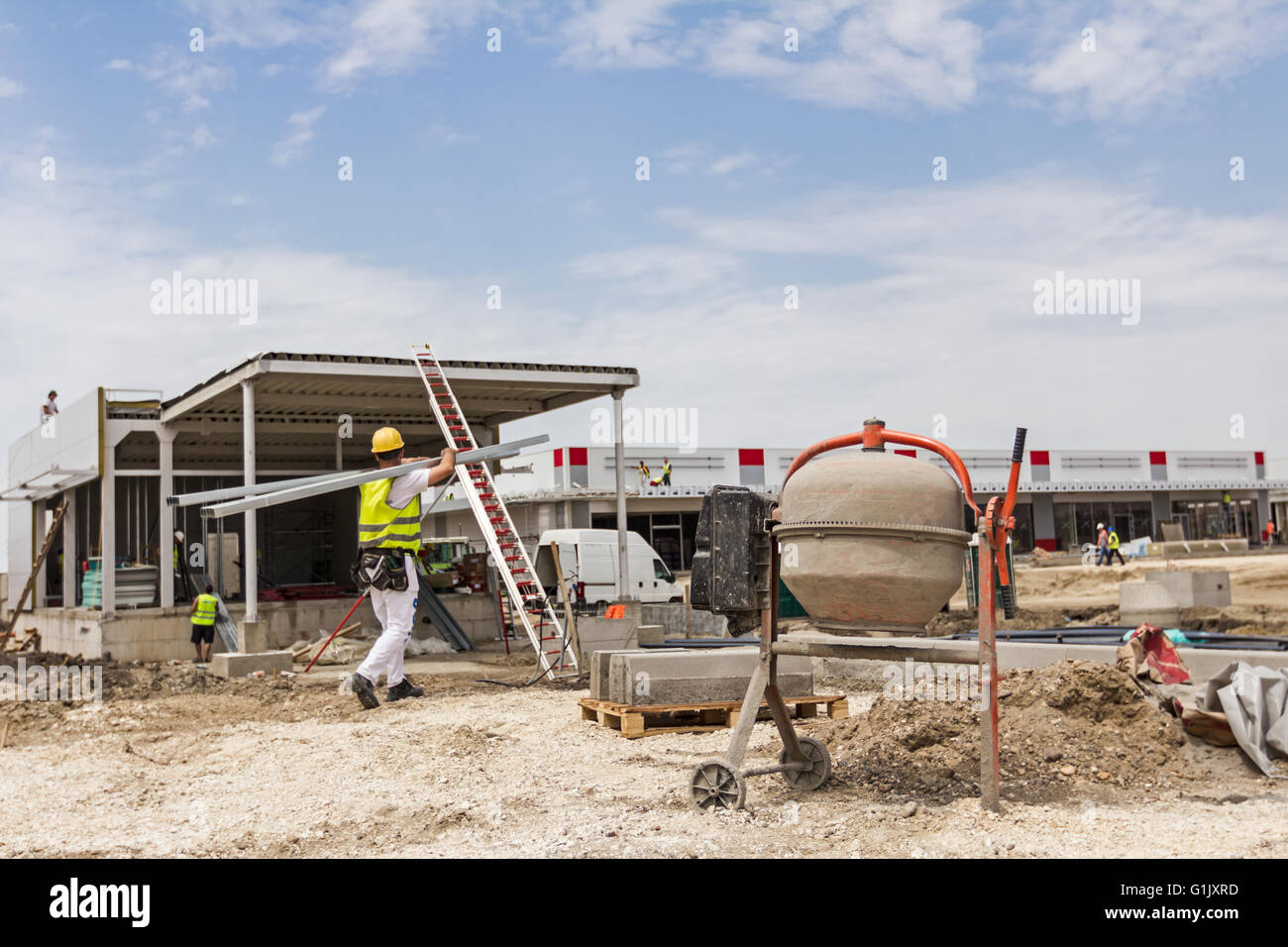 Cement mixer machine at construction site, tools, sand and cement bag ...