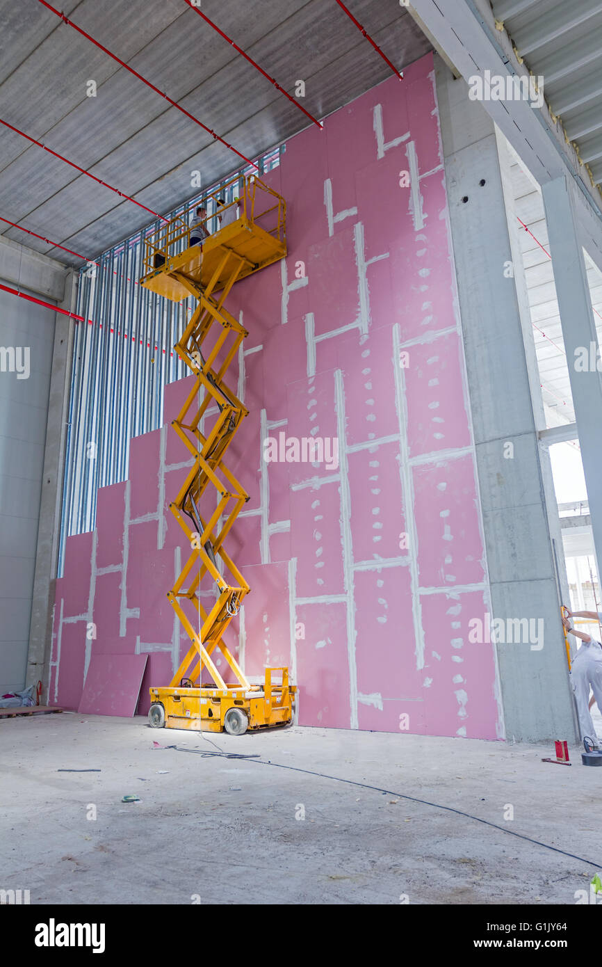Workers are high up in cherry picker on building site Stock Photo - Alamy