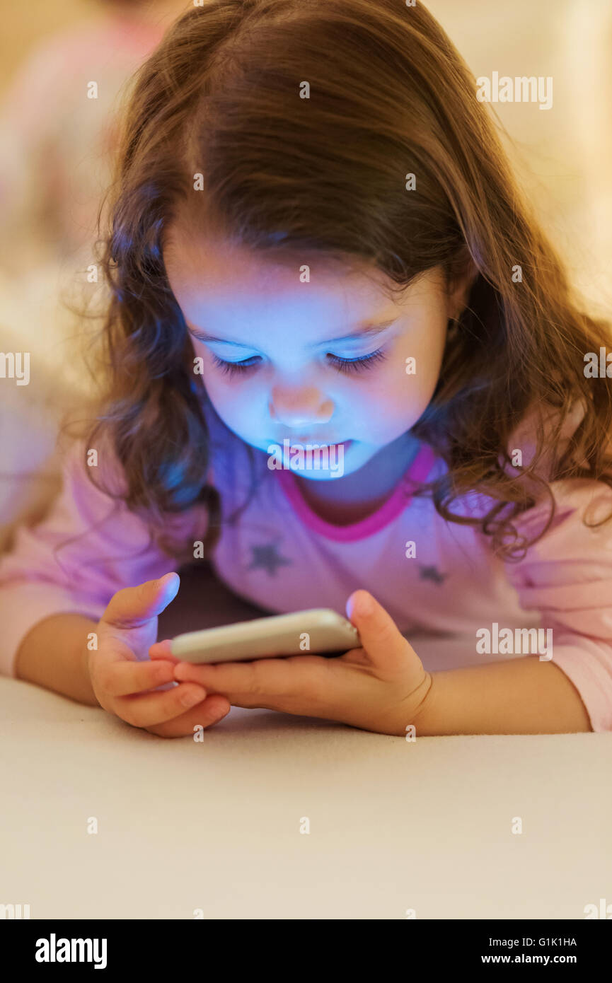 Little girl with smartphone lying in a bed, bedtime Stock Photo - Alamy
