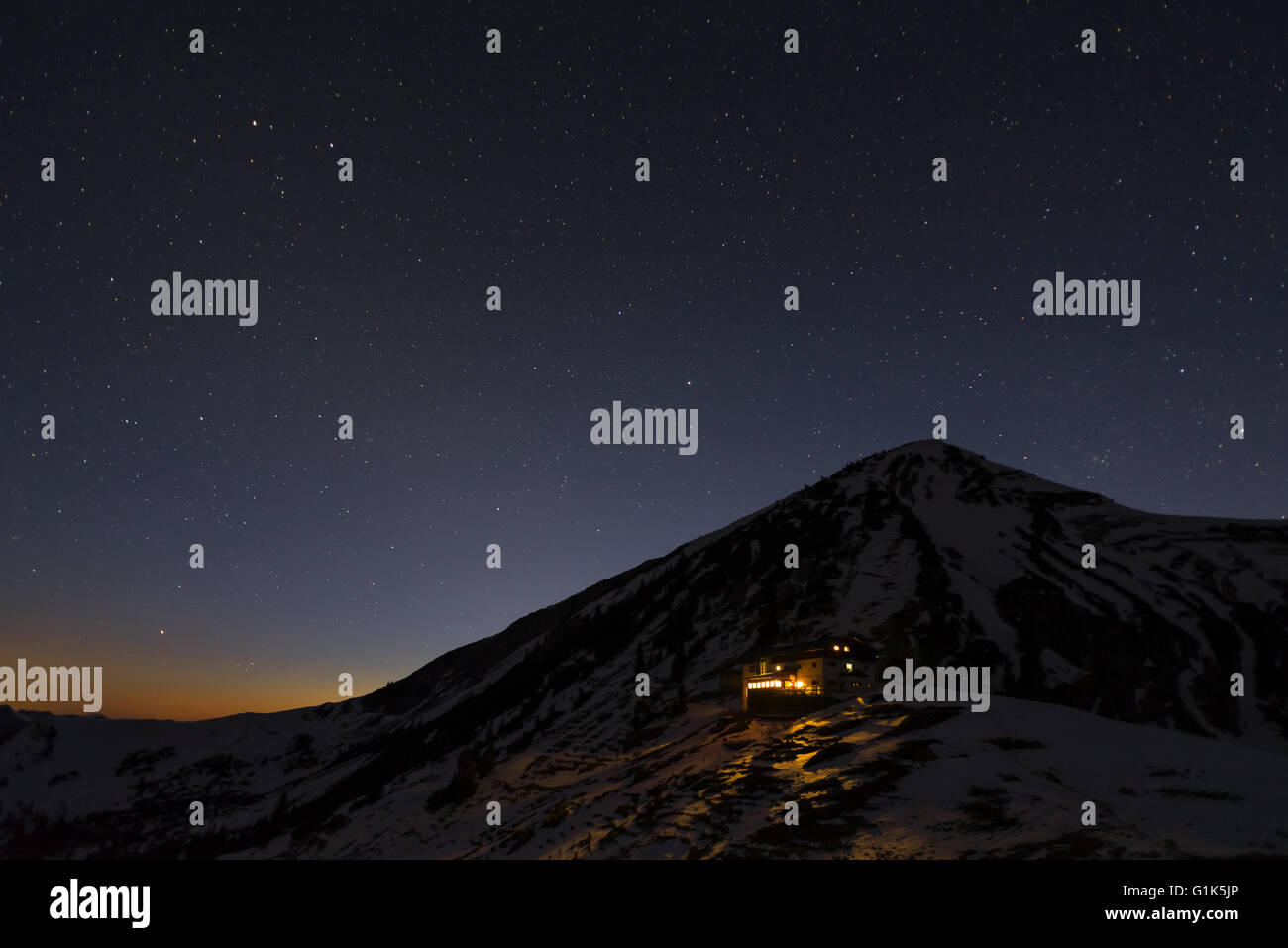Starry night sky and light shining from the Toelzer alpine hut in the ...