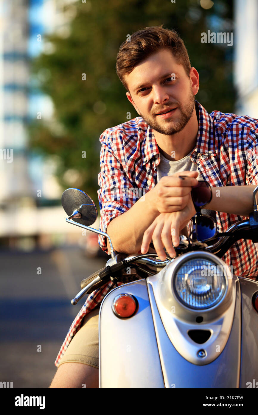 fashionable young man riding a vintage scooter in street Stock Photo ...