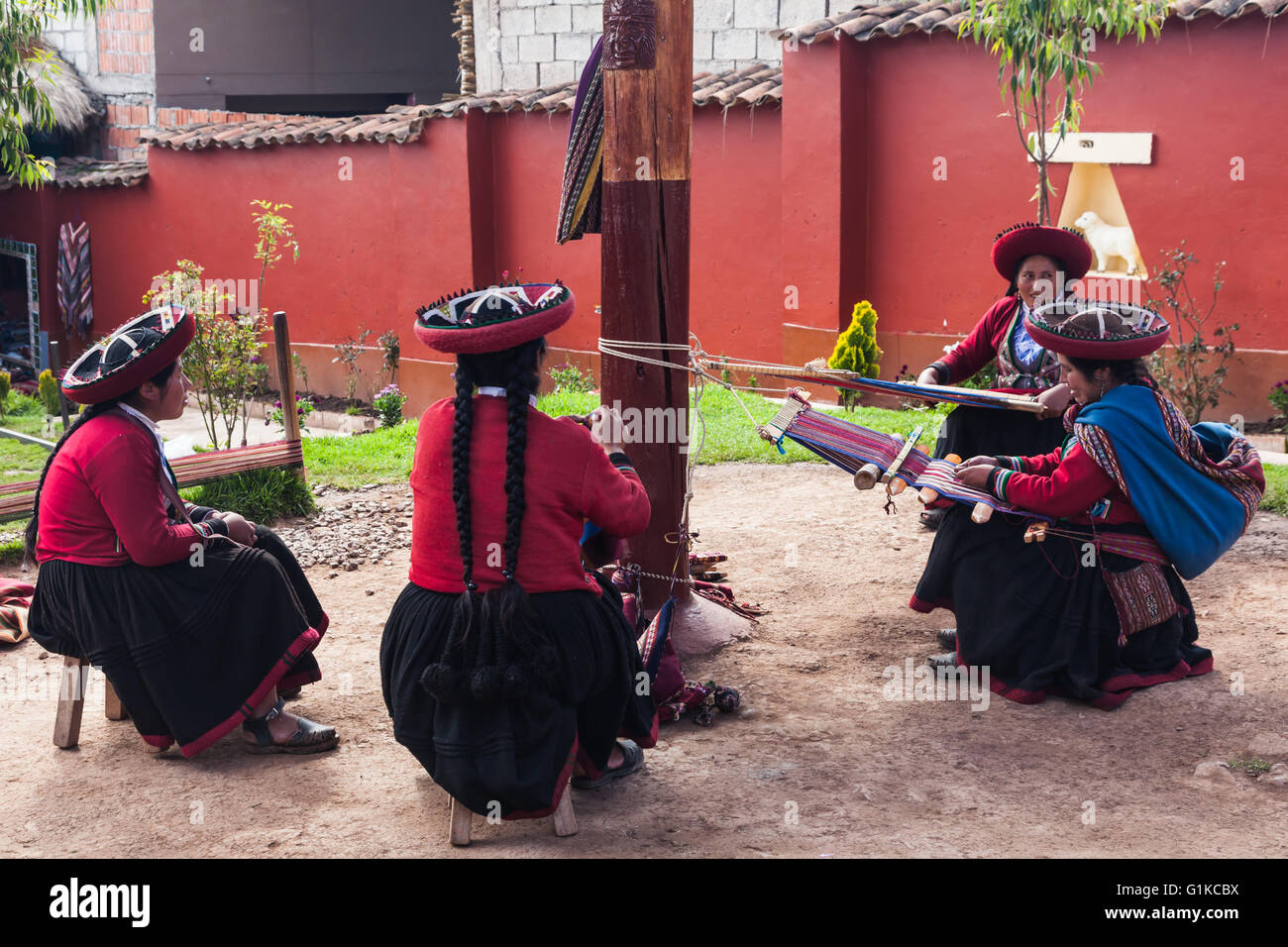 Group of women in conversation while hand weaving colorful fabrics in ...