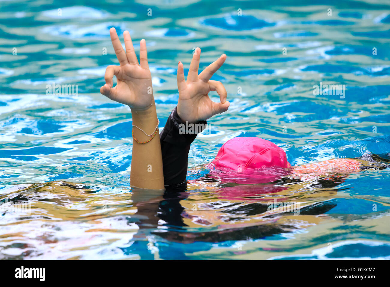 gesturing OK sign from hand of young girls come up from water Stock ...