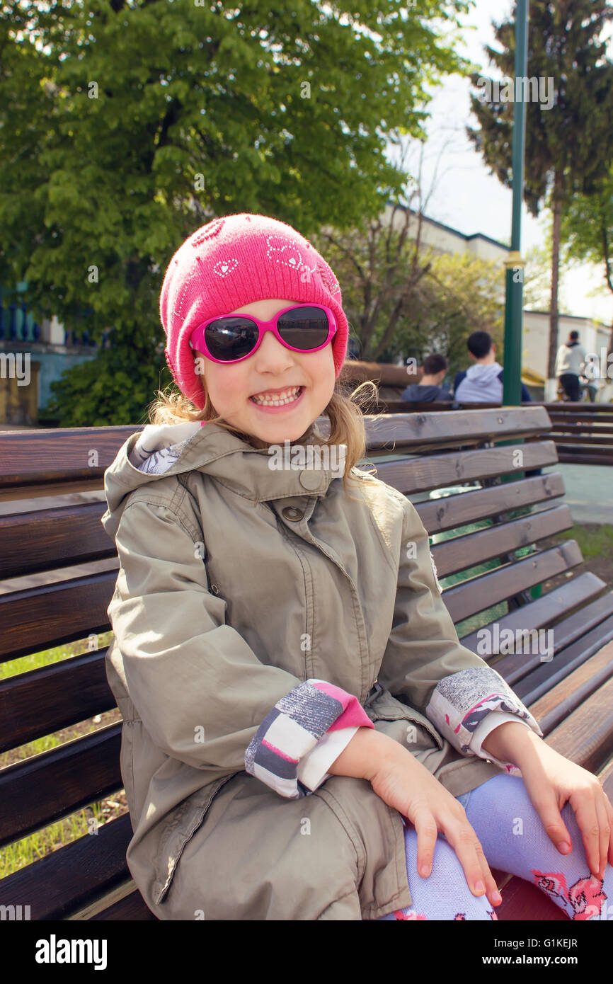 Little girl sitting on bench Stock Photo - Alamy