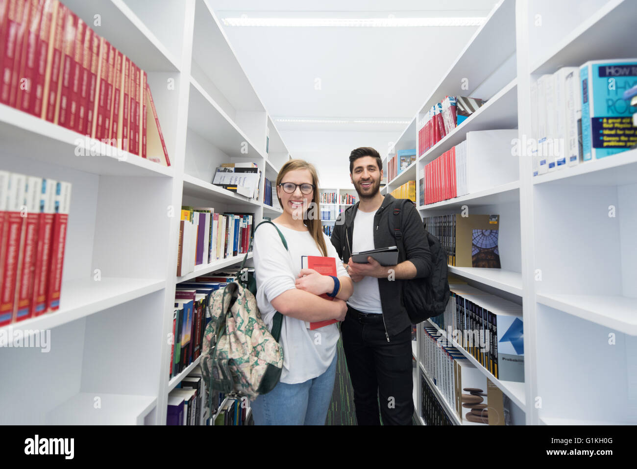 happy students group in school library selecting books to read and ...