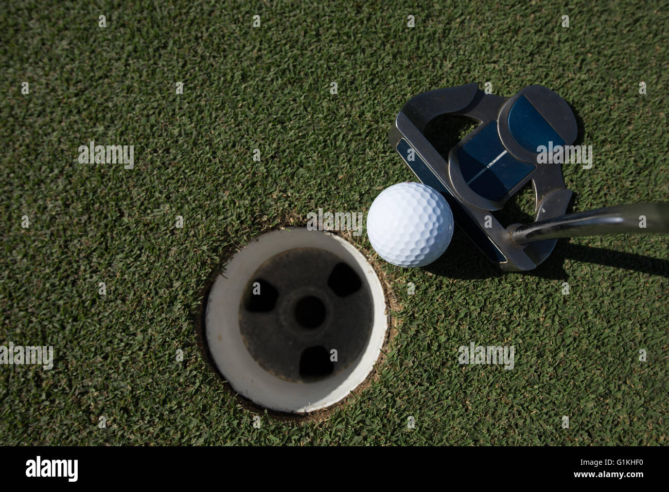 close up of putter hitting golf ball to hole at course Stock Photo - Alamy