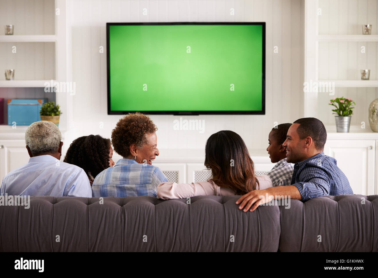Multi generation family watching TV and laughing, back view Stock Photo - Alamy