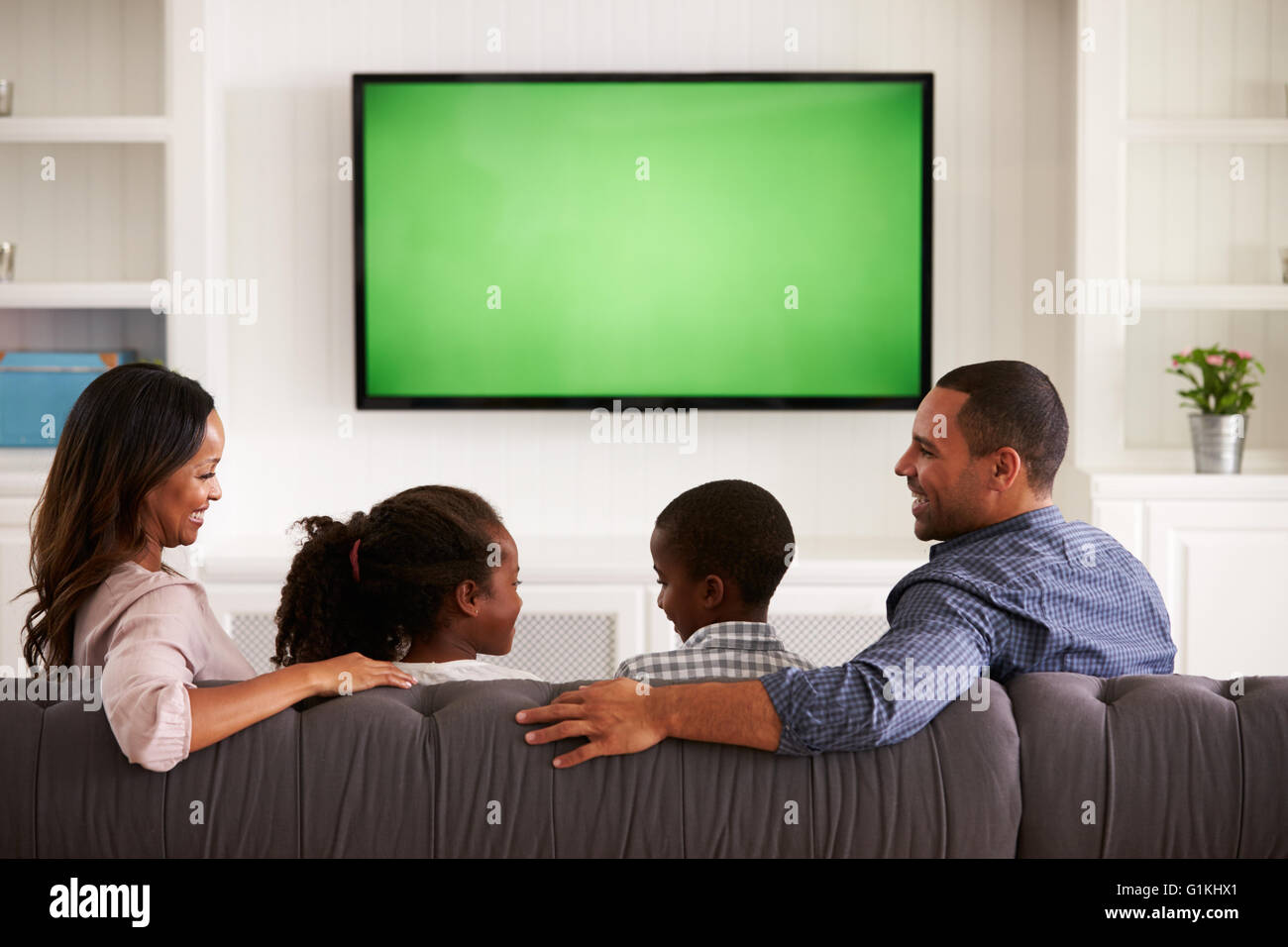 Parents and children watching TV, looking at each other Stock Photo - Alamy