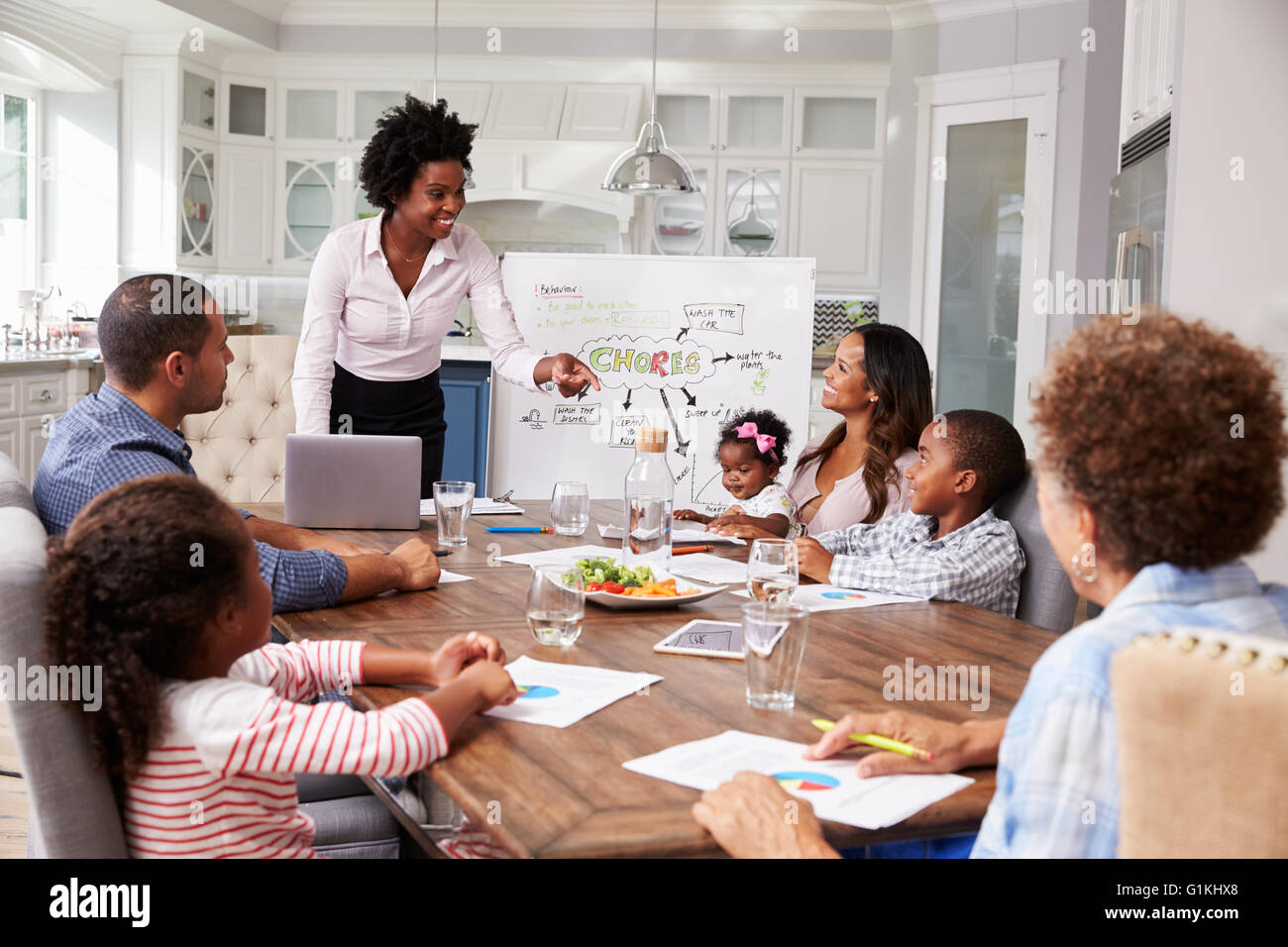 Businesswoman presents meeting to a family in their kitchen Stock Photo ...