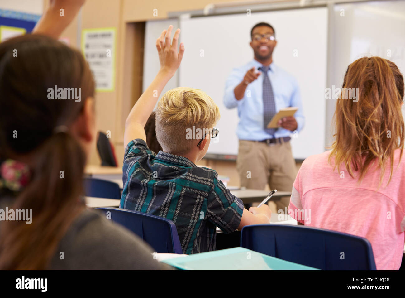Kids raising hands to answer in an elementary school class Stock Photo ...