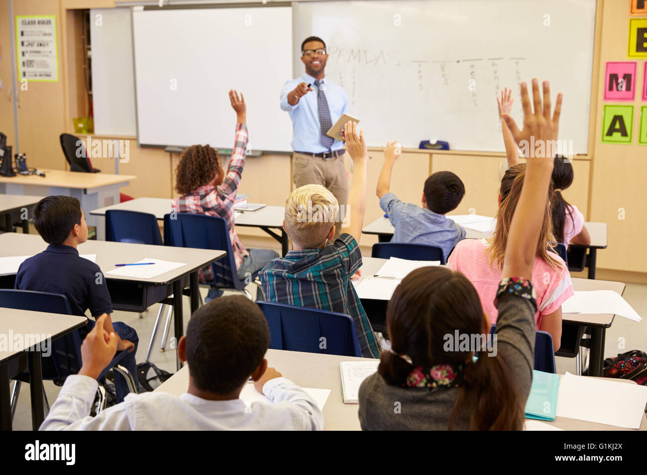 Kids raising hands to answer in an elementary school class Stock Photo ...