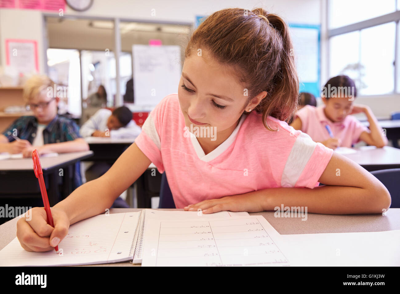 Schoolgirl writing at her desk in an elementary school class Stock ...