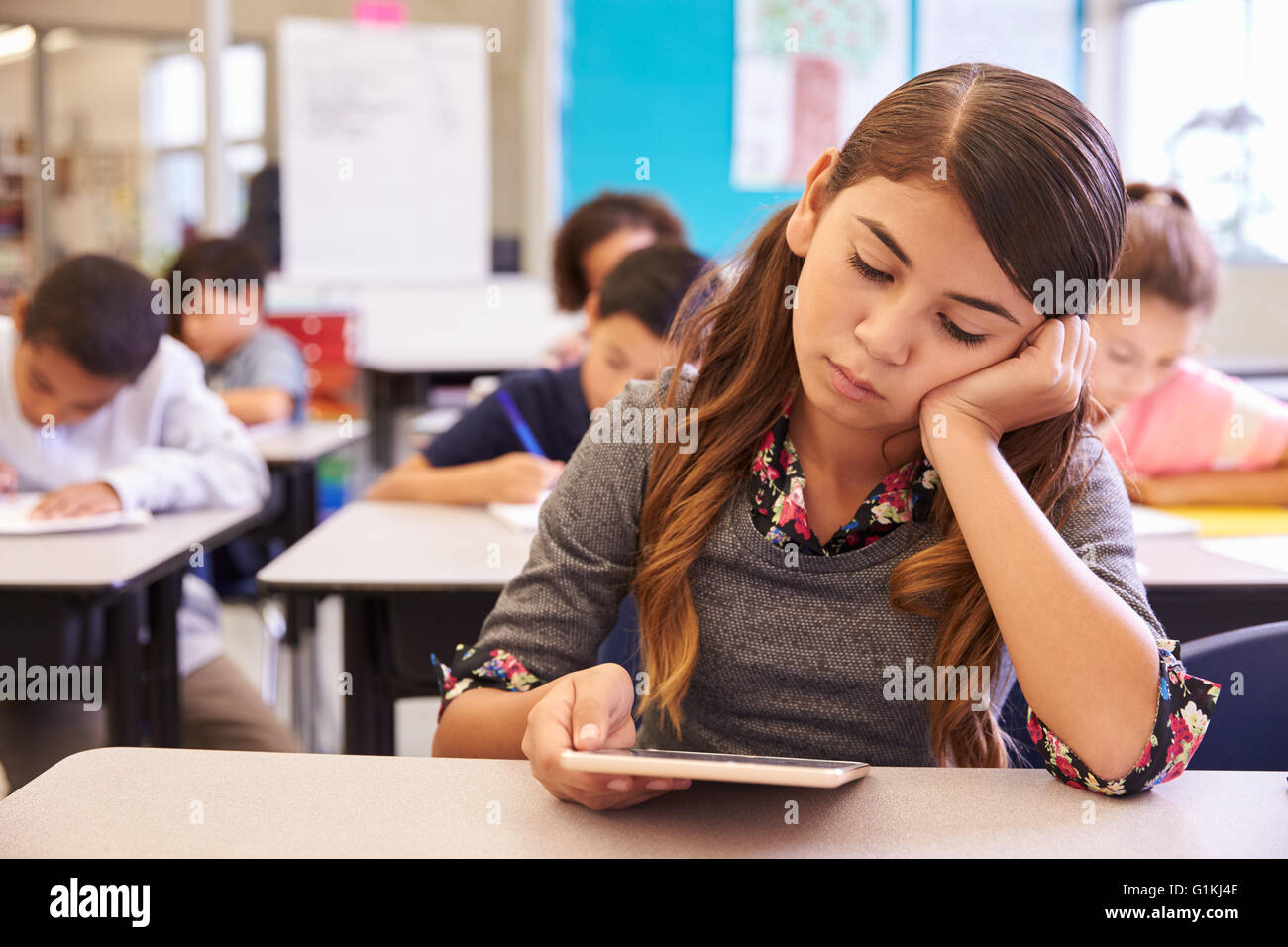Bored girl reading tablet in elementary school class Stock Photo - Alamy