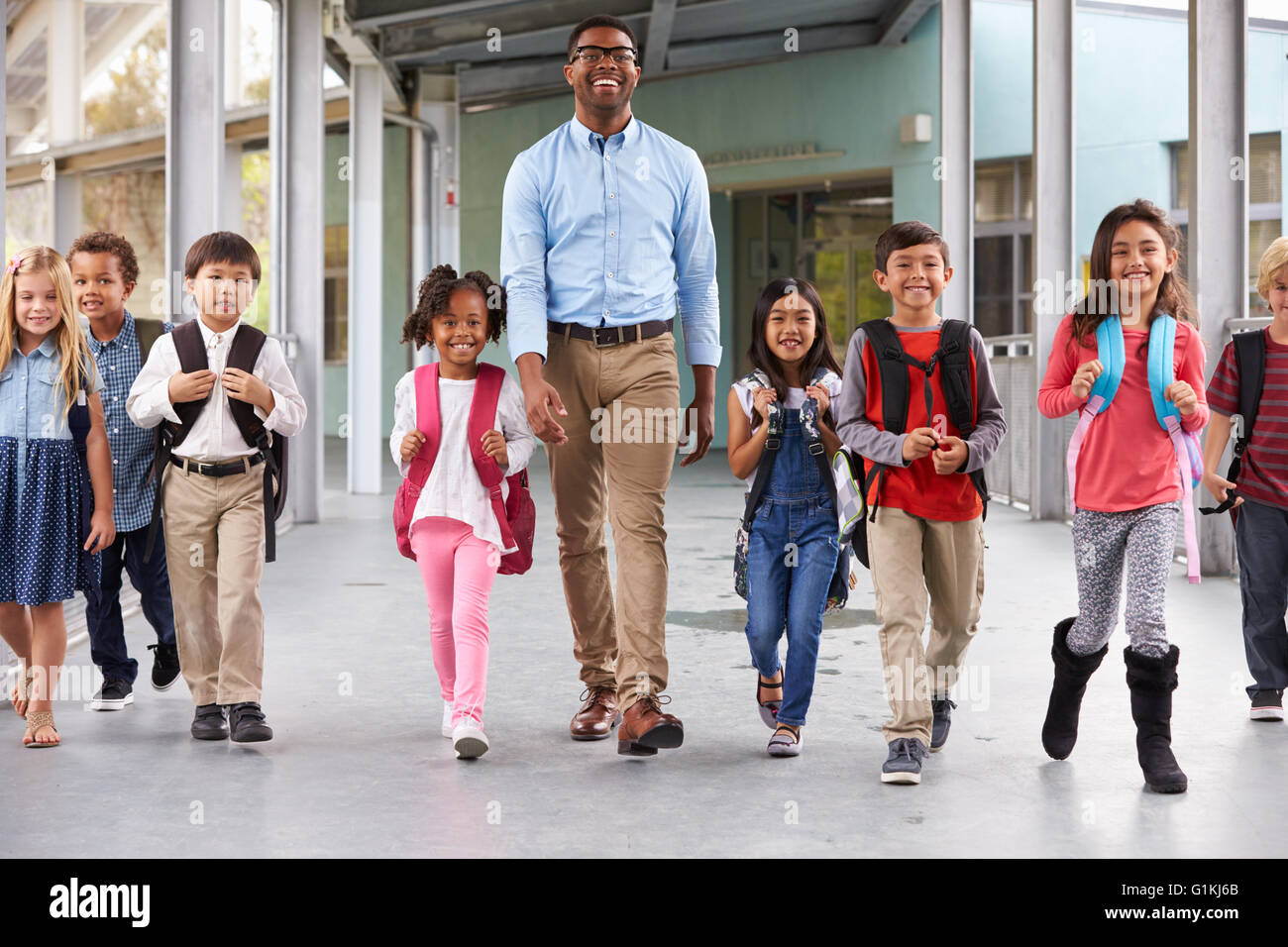 Male teacher walking in corridor with elementary school kids Stock ...