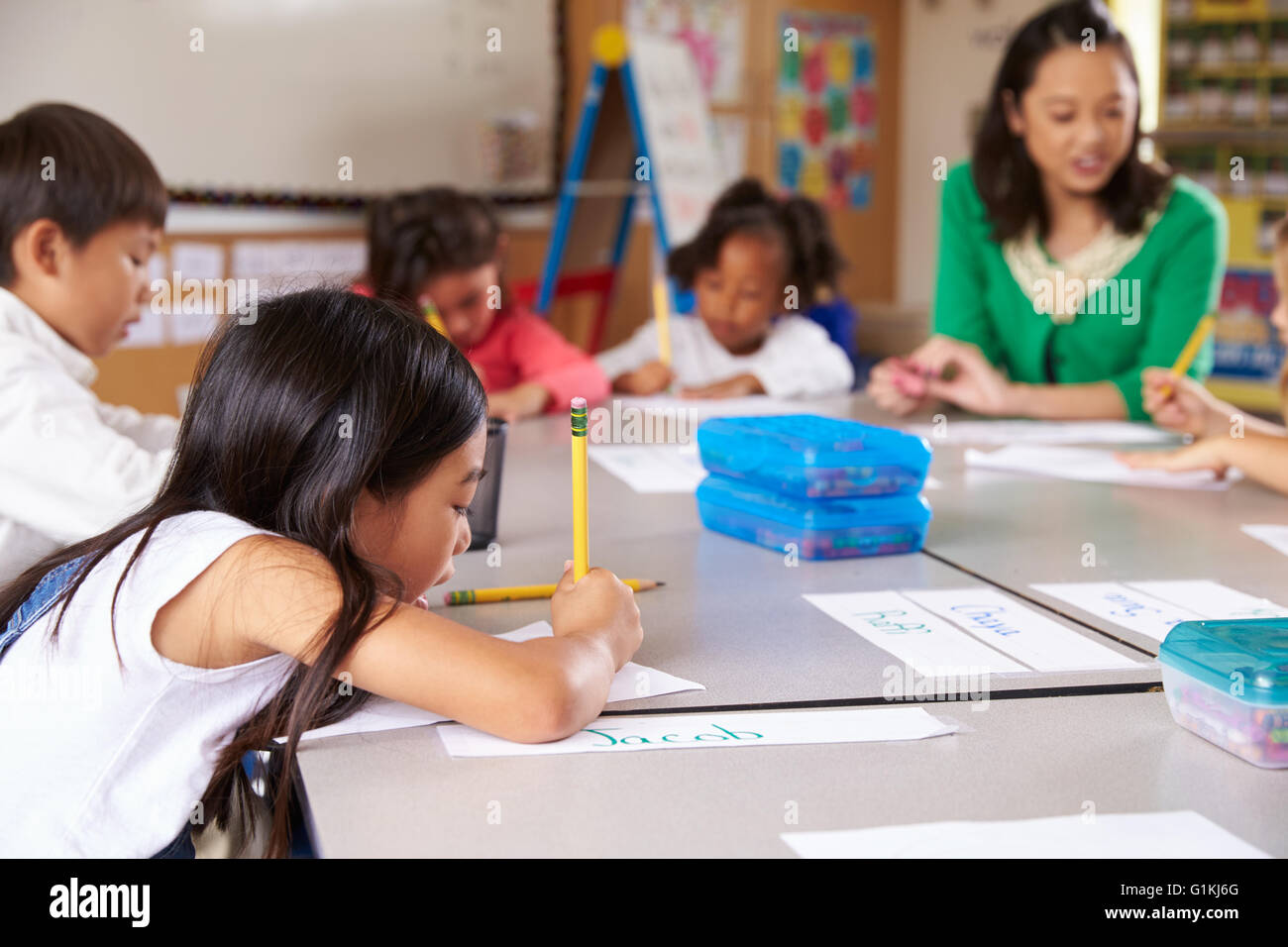 Teacher sitting with kids in elementary school lesson Stock Photo - Alamy