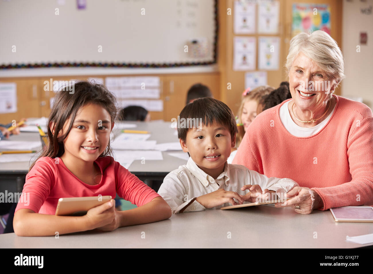 Senior teacher and elementary school pupils in classroom Stock Photo ...