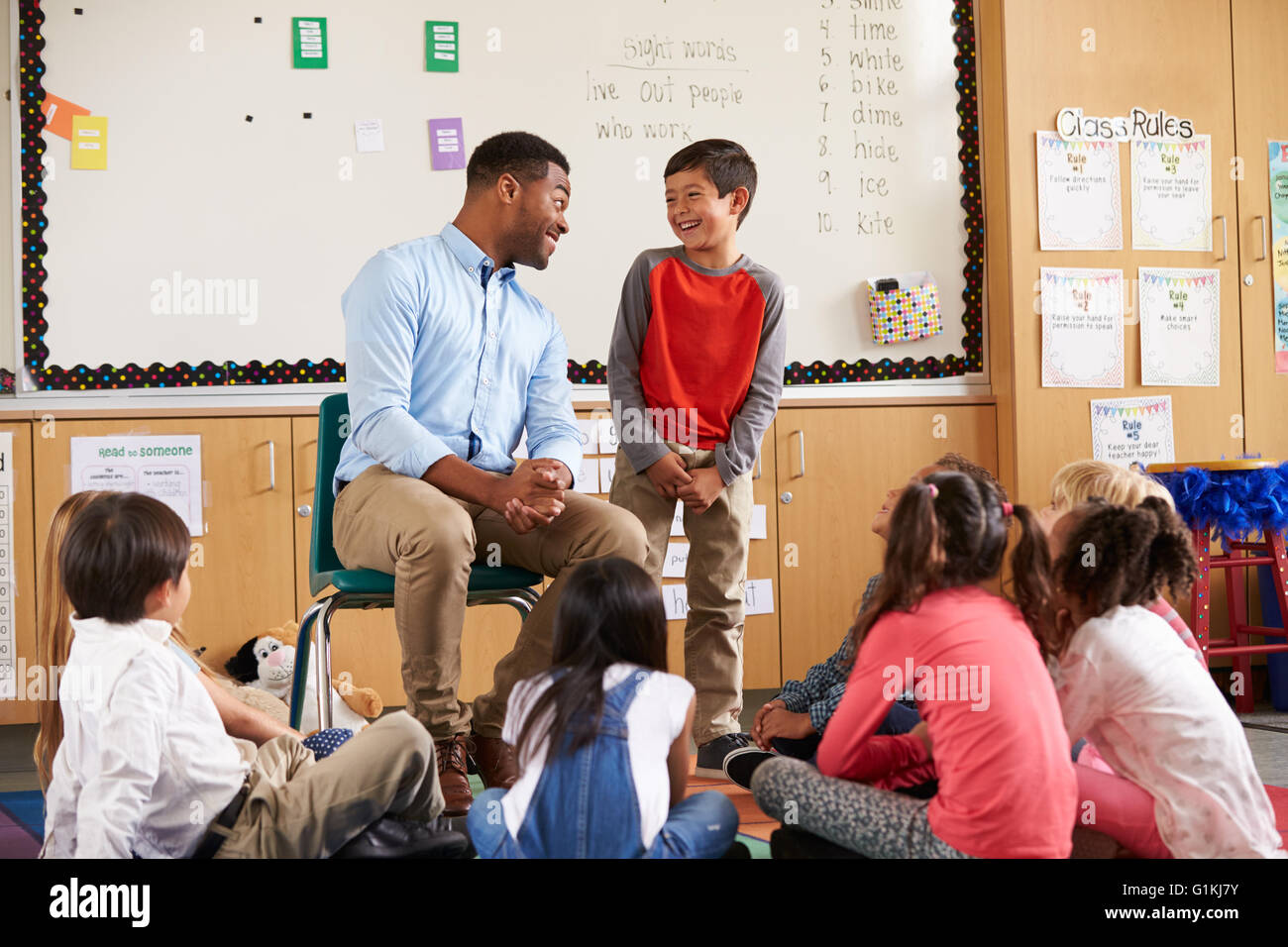 Schoolboy at front of elementary class talking with teacher Stock Photo ...
