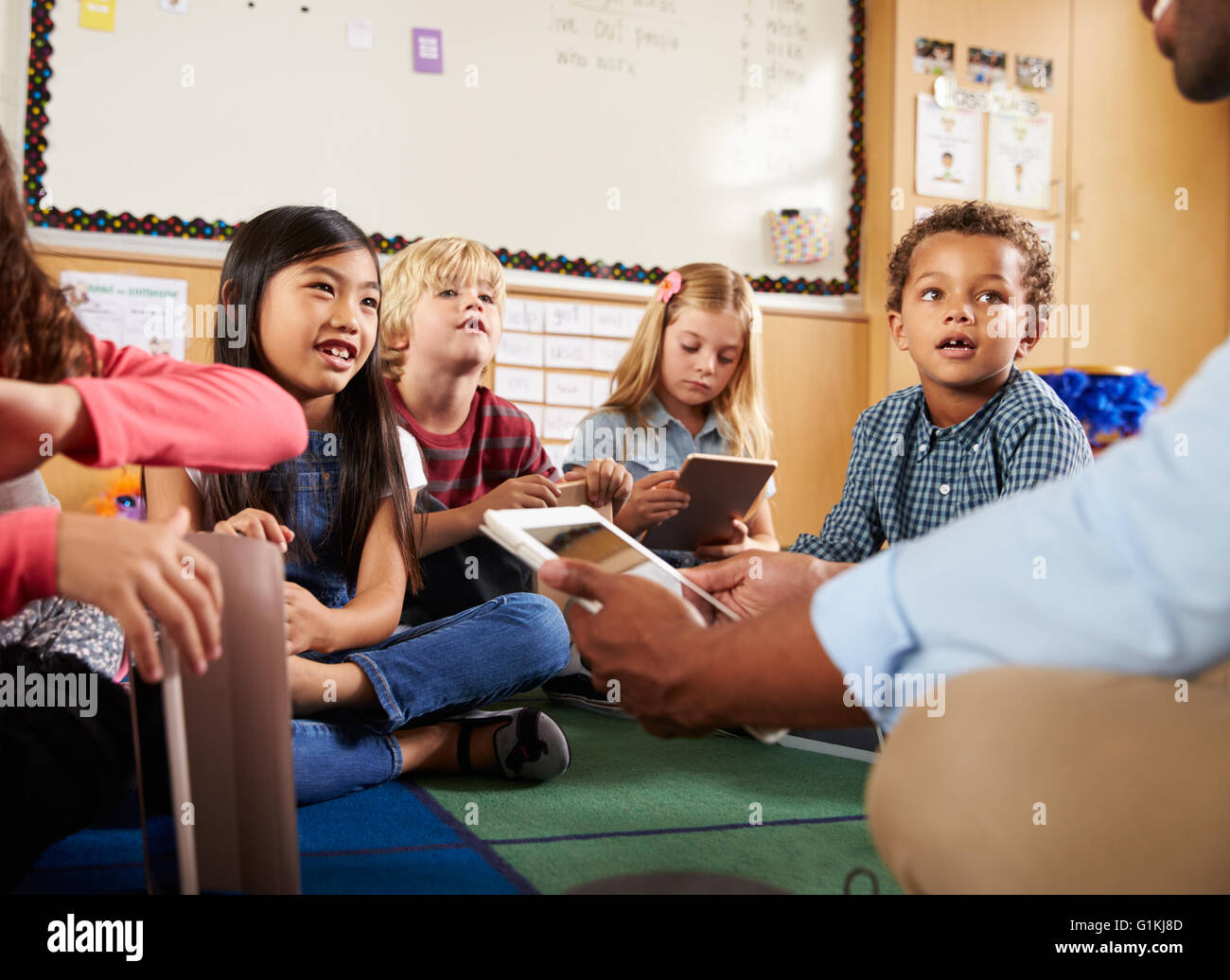 Elementary school class sitting cross legged using tablets Stock Photo ...