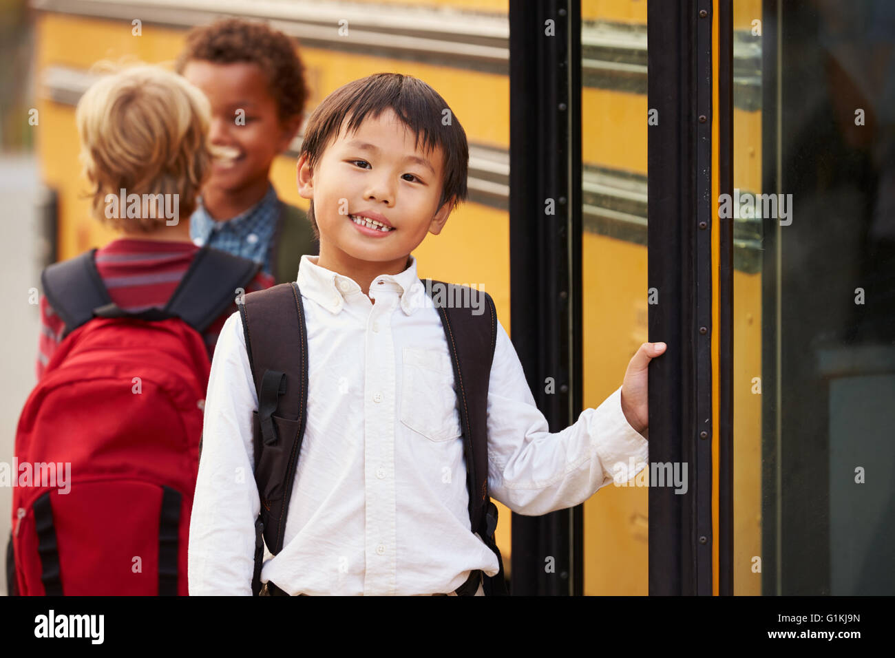 Elementary school boy at the front of the school bus queue Stock Photo ...