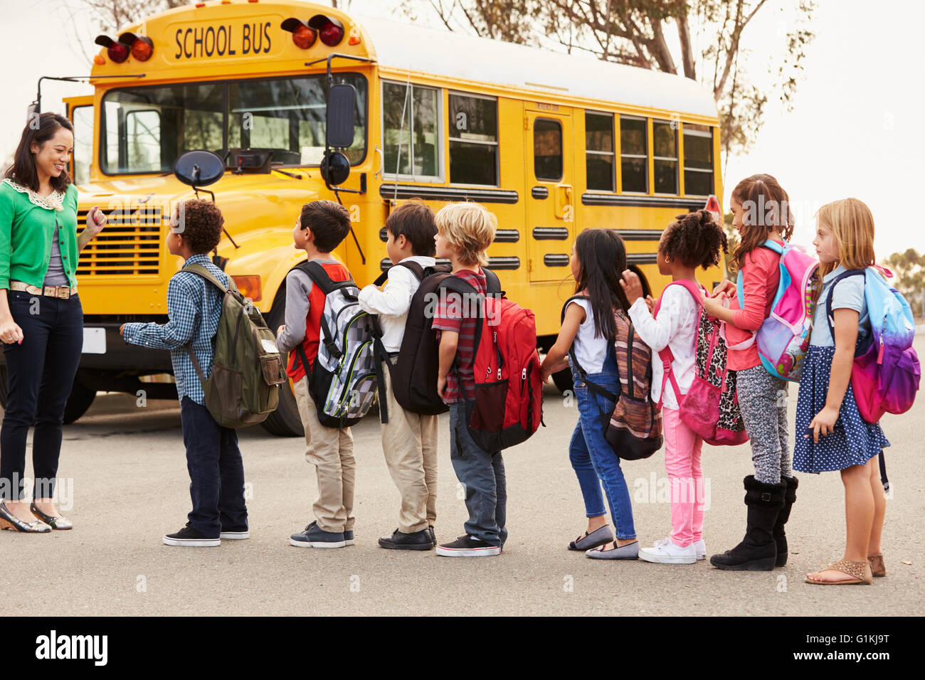 Teacher and a group of elementary school kids at a bus stop Stock Photo ...