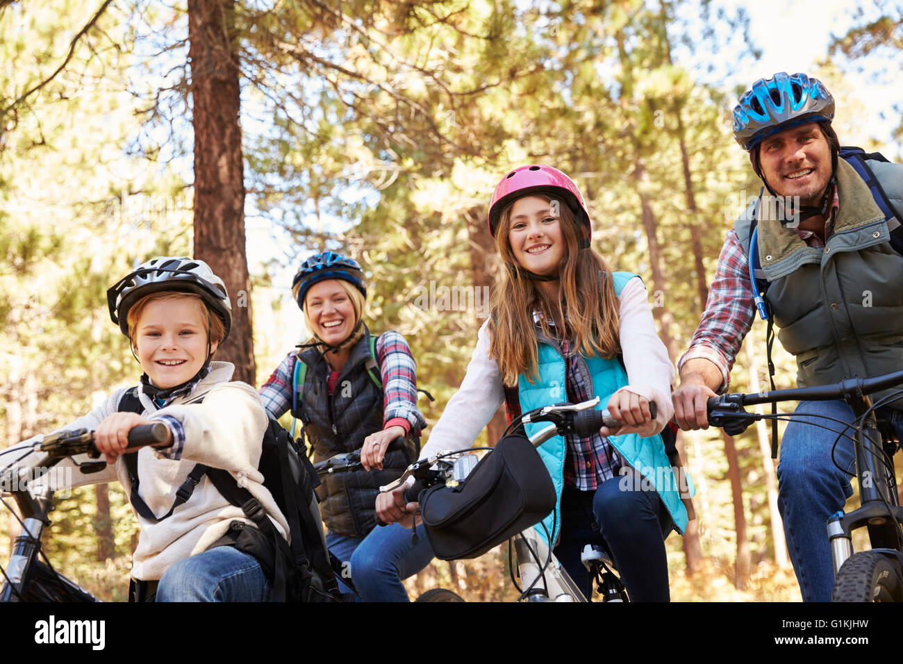 Family mountain biking in a forest, looking to camera Stock Photo - Alamy