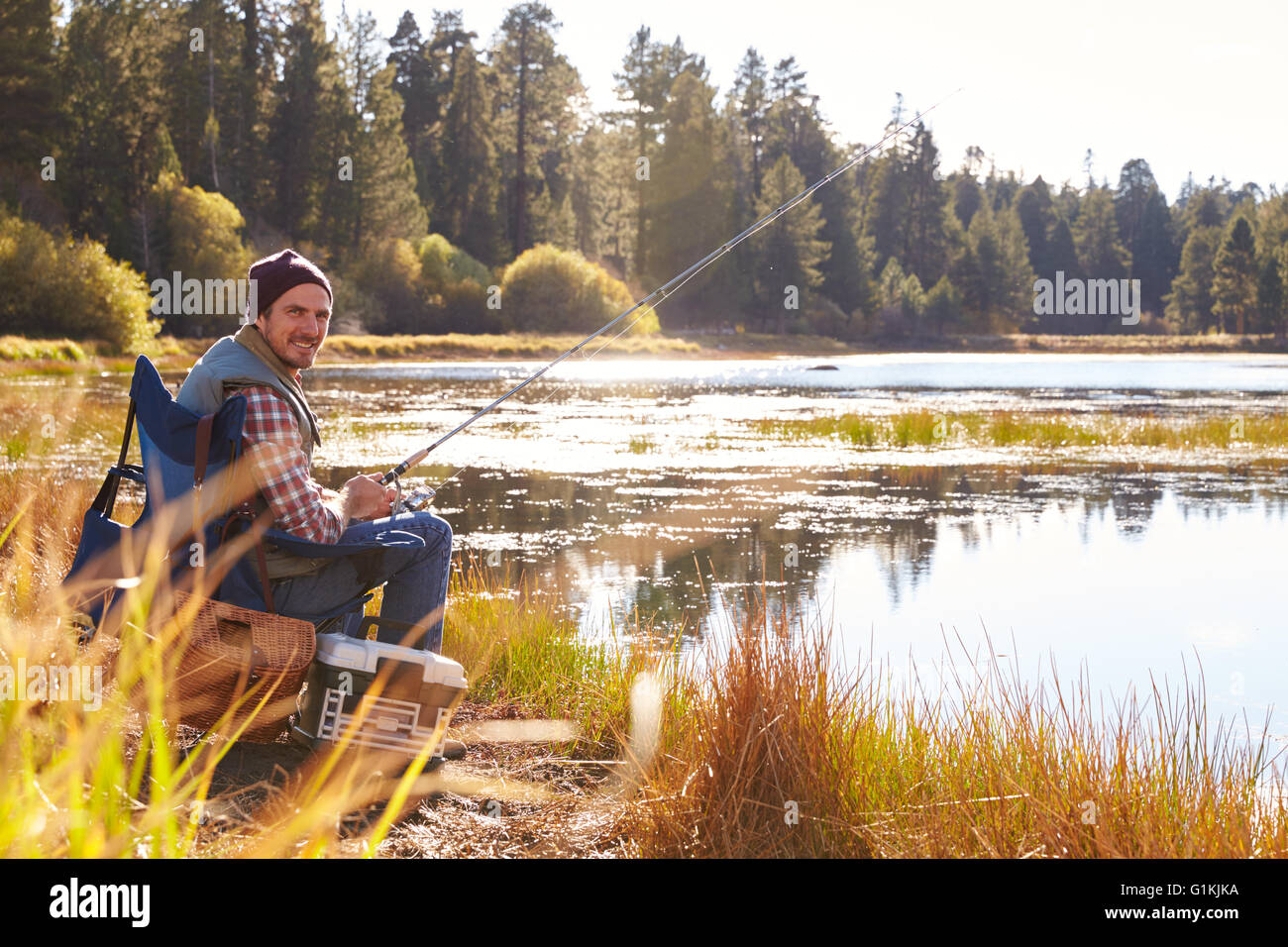 Mid-adult man fishing by lakeside, looking to camera Stock Photo - Alamy