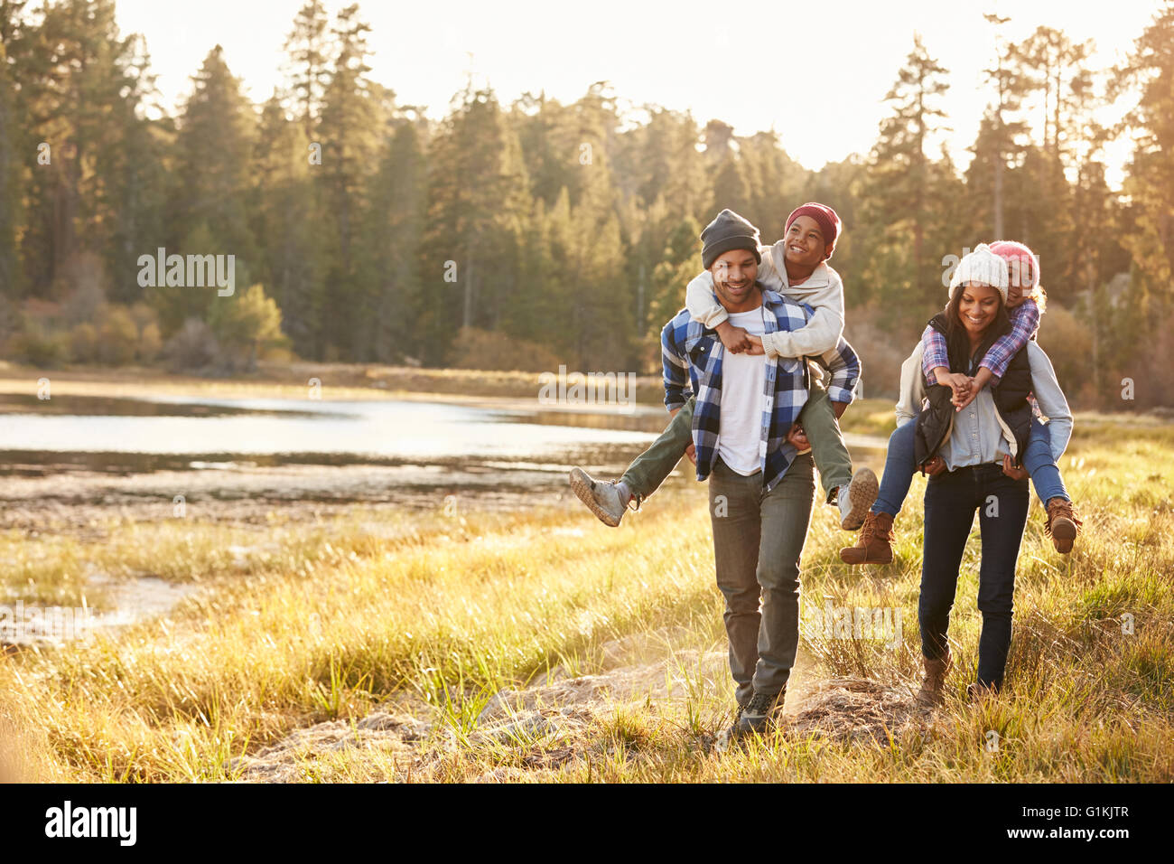 Parents Giving Children Piggyback Ride On Walk By Lake Stock Photo - Alamy