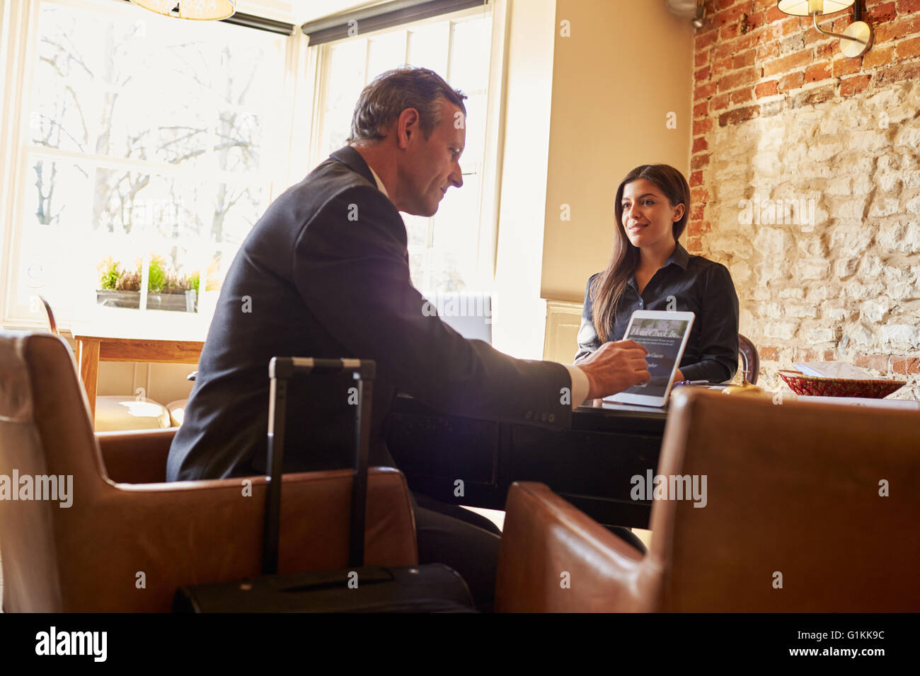 Guest checking in at hotel reception using tablet computer Stock Photo ...