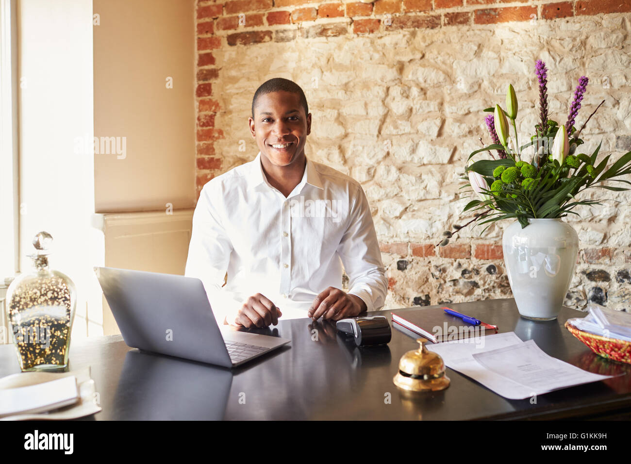 Concierge working at the check in desk of a boutique hotel Stock Photo ...