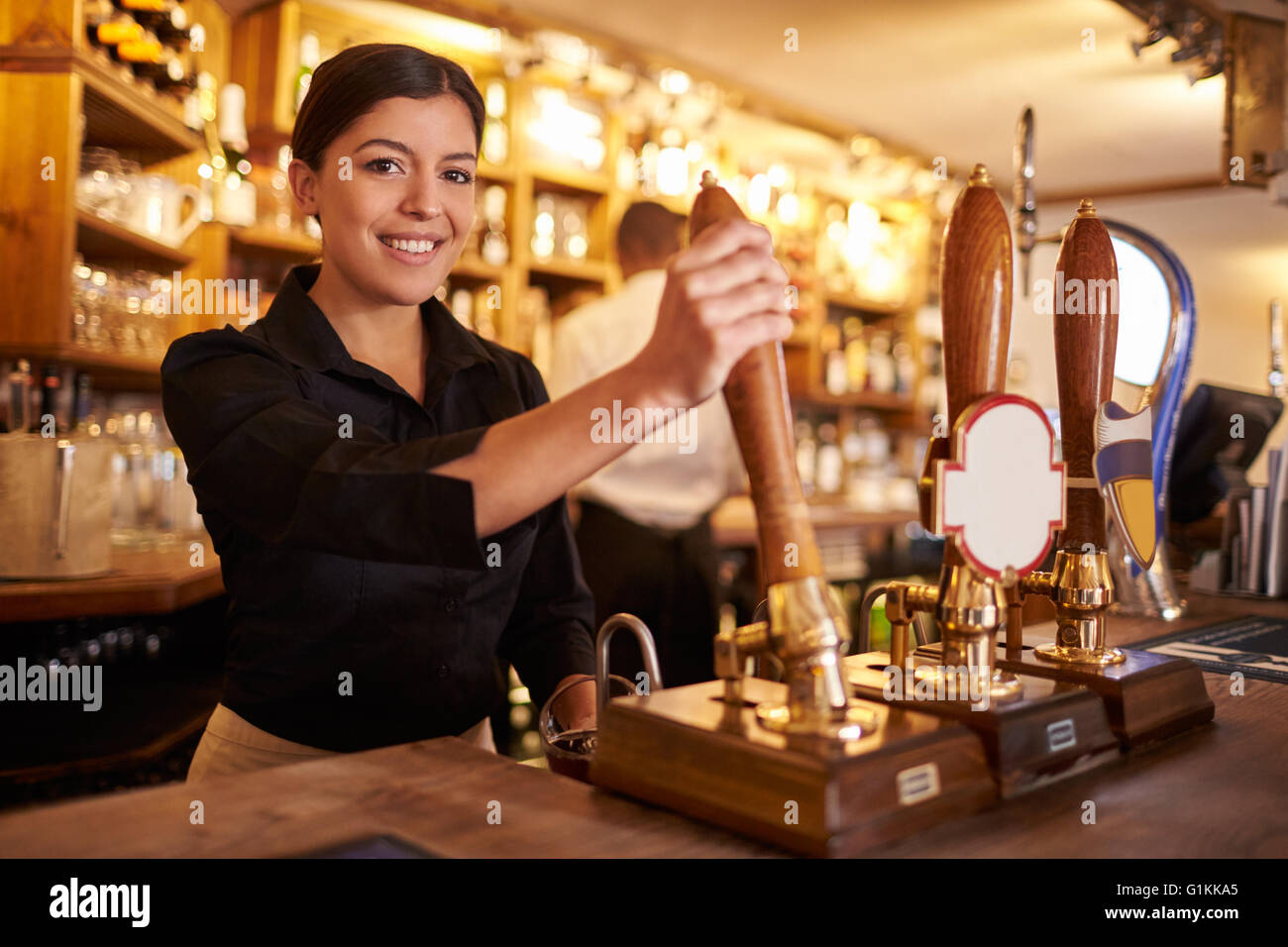 A young woman working behind a bar looking to camera, horizontal Stock ...