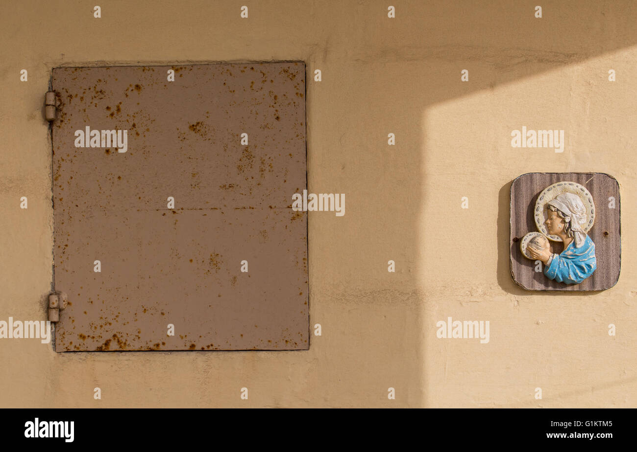 Wall of a house, with a picture of a saint enlightened by the sun and ...