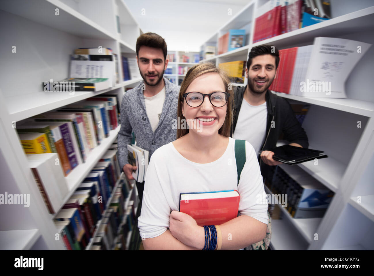 happy students group in school library selecting books to read and ...