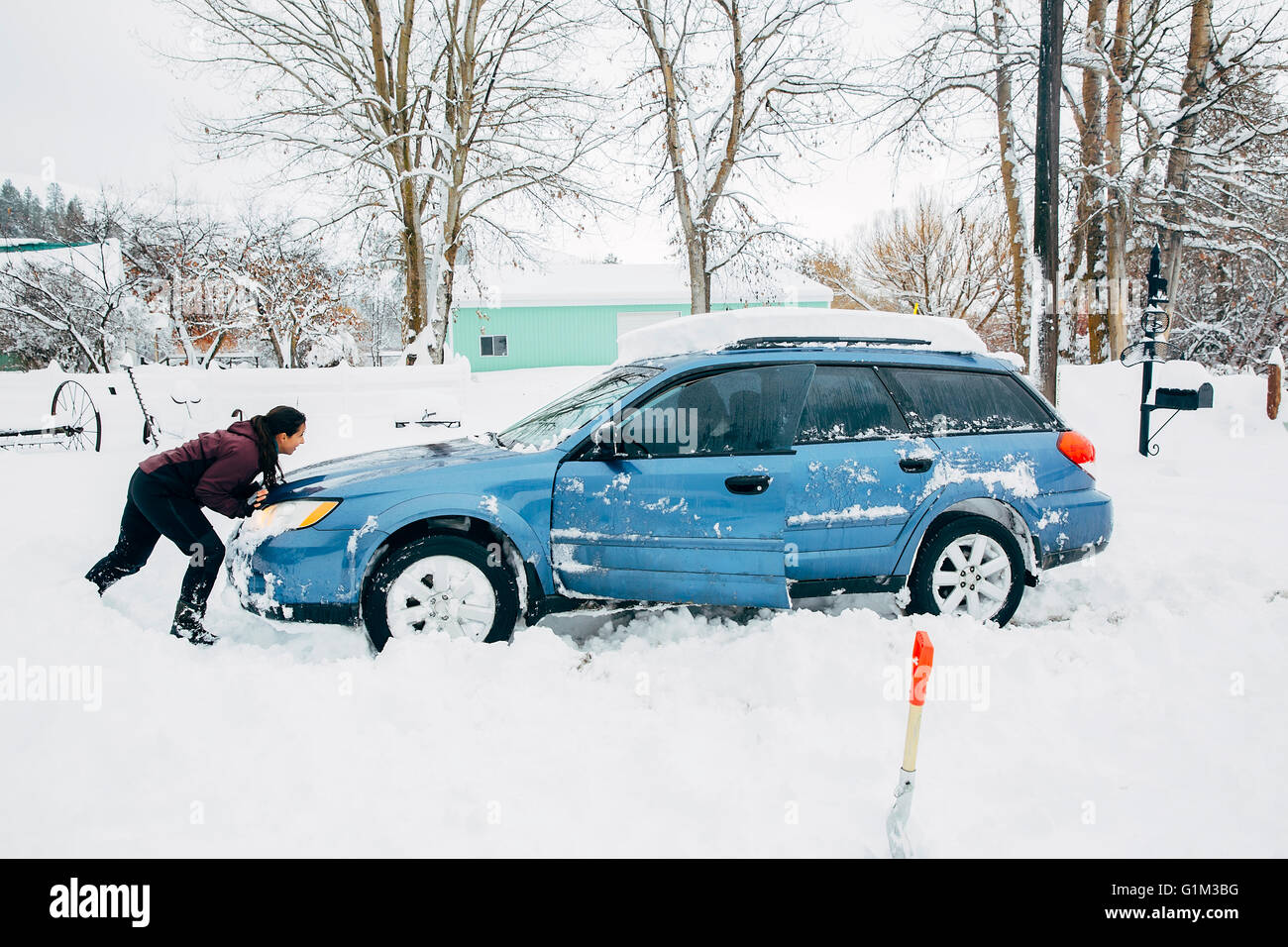 Caucasian woman pushing car stuck in snow Stock Photo - Alamy