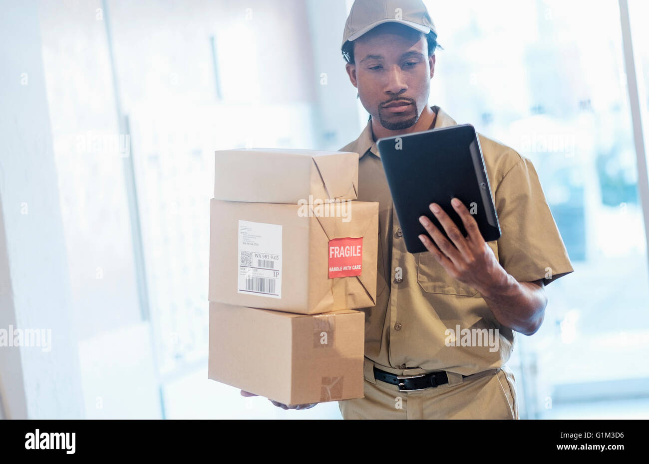 Black delivery man using digital tablet Stock Photo - Alamy