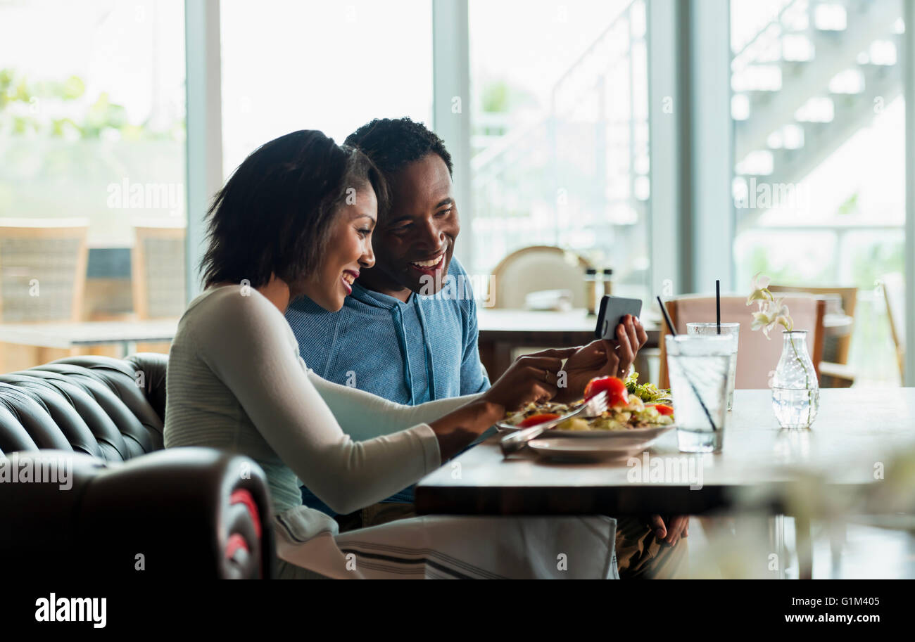 Couple using cell phone at lunch in cafe Stock Photo - Alamy
