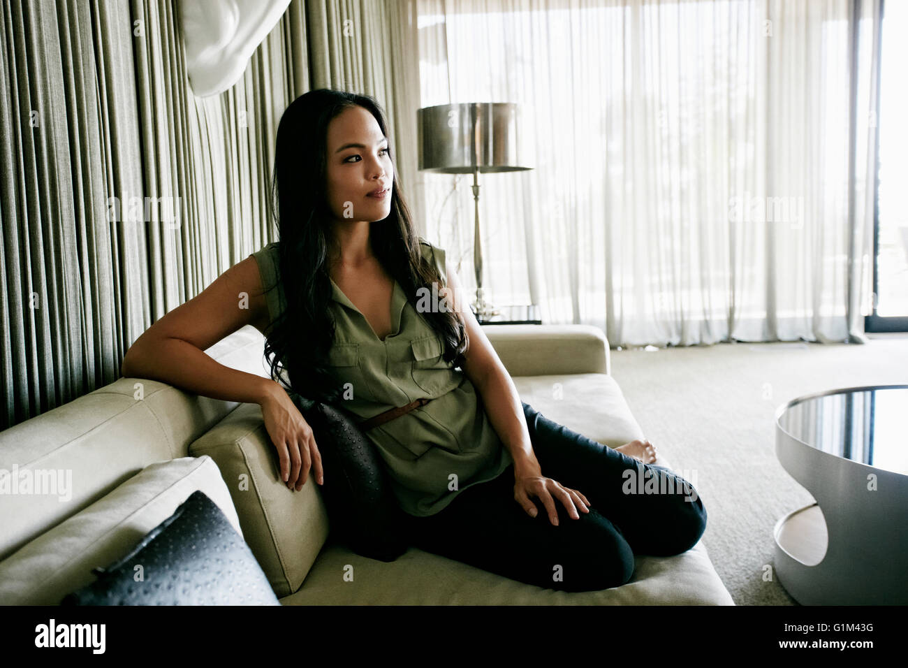 Chinese woman sitting on sofa Stock Photo - Alamy