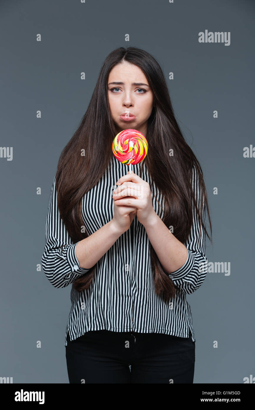 Sad woman holding lollipop over gray background Stock Photo - Alamy