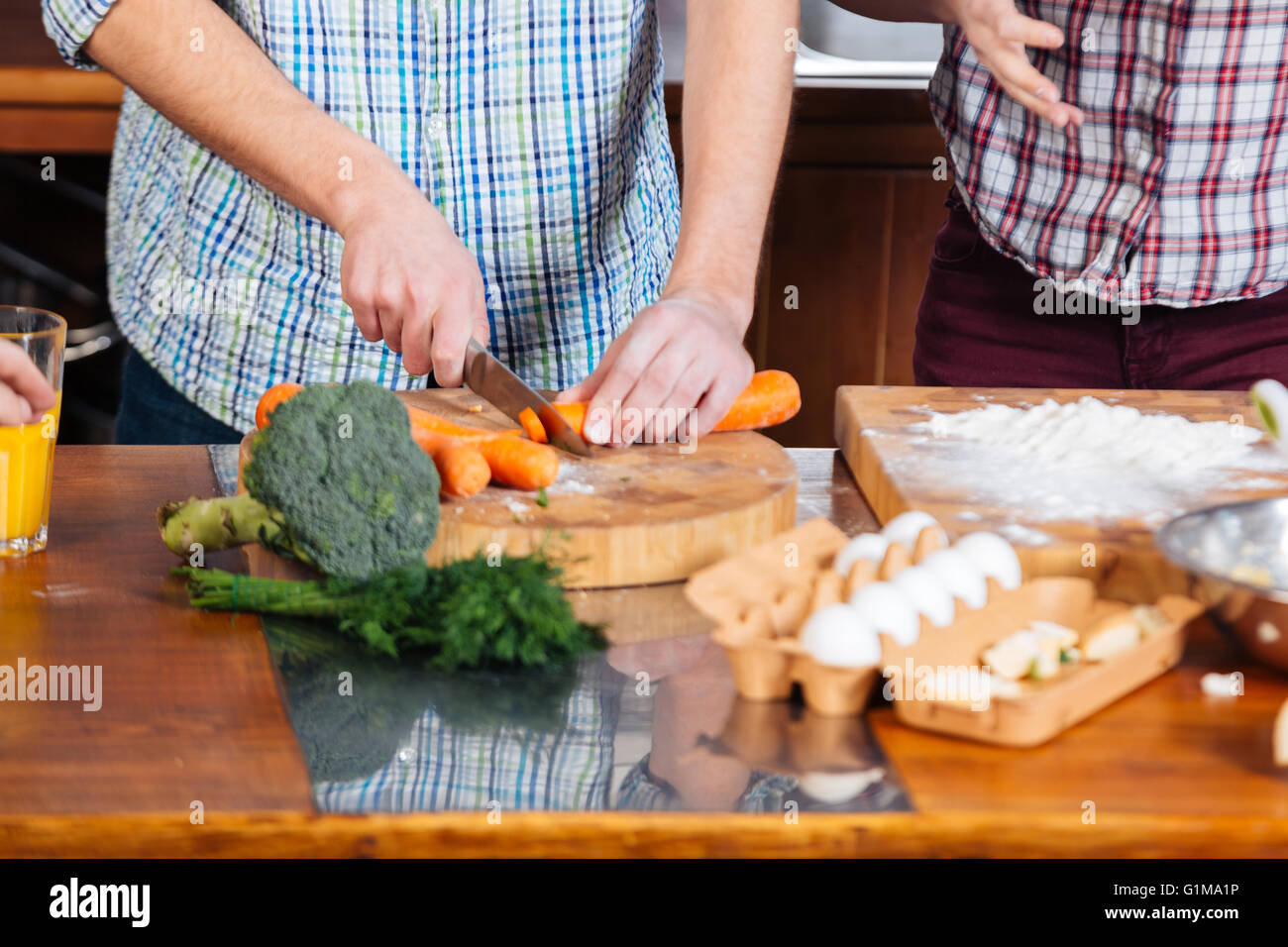 Hands of young couple cooking and cutting carrots on the kitchen Stock ...